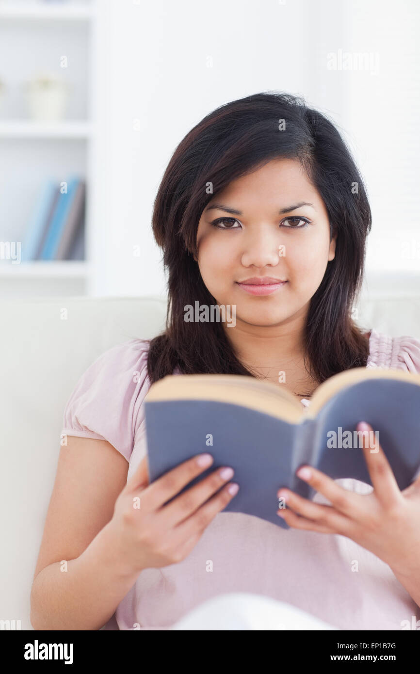Woman reading a book while she sits on a couch Stock Photo - Alamy