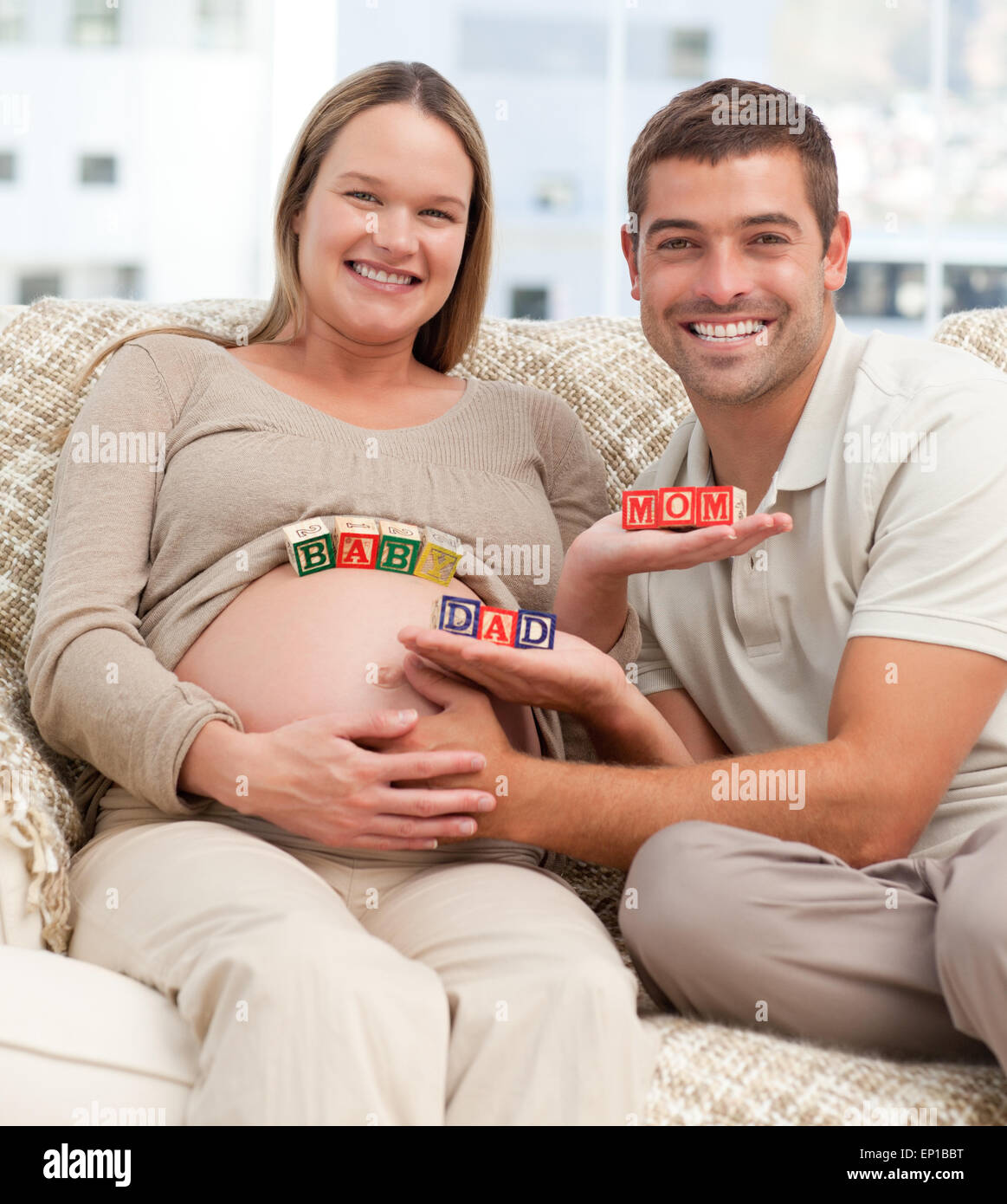 Lovely future parents holding cubes forming the words mom ,dad and baby ...