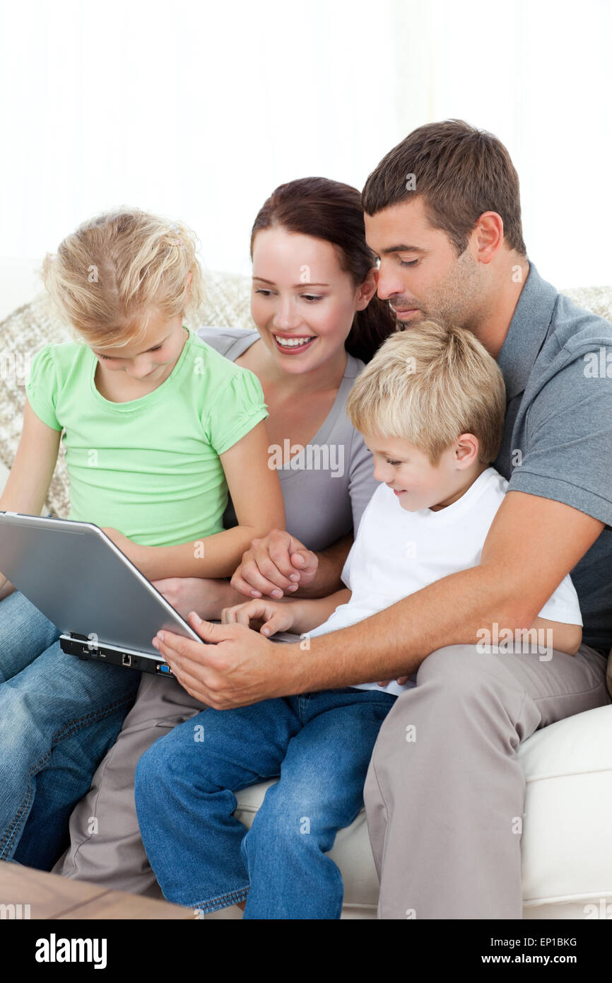 Parents and children using their laptop together sitting on the sofa ...