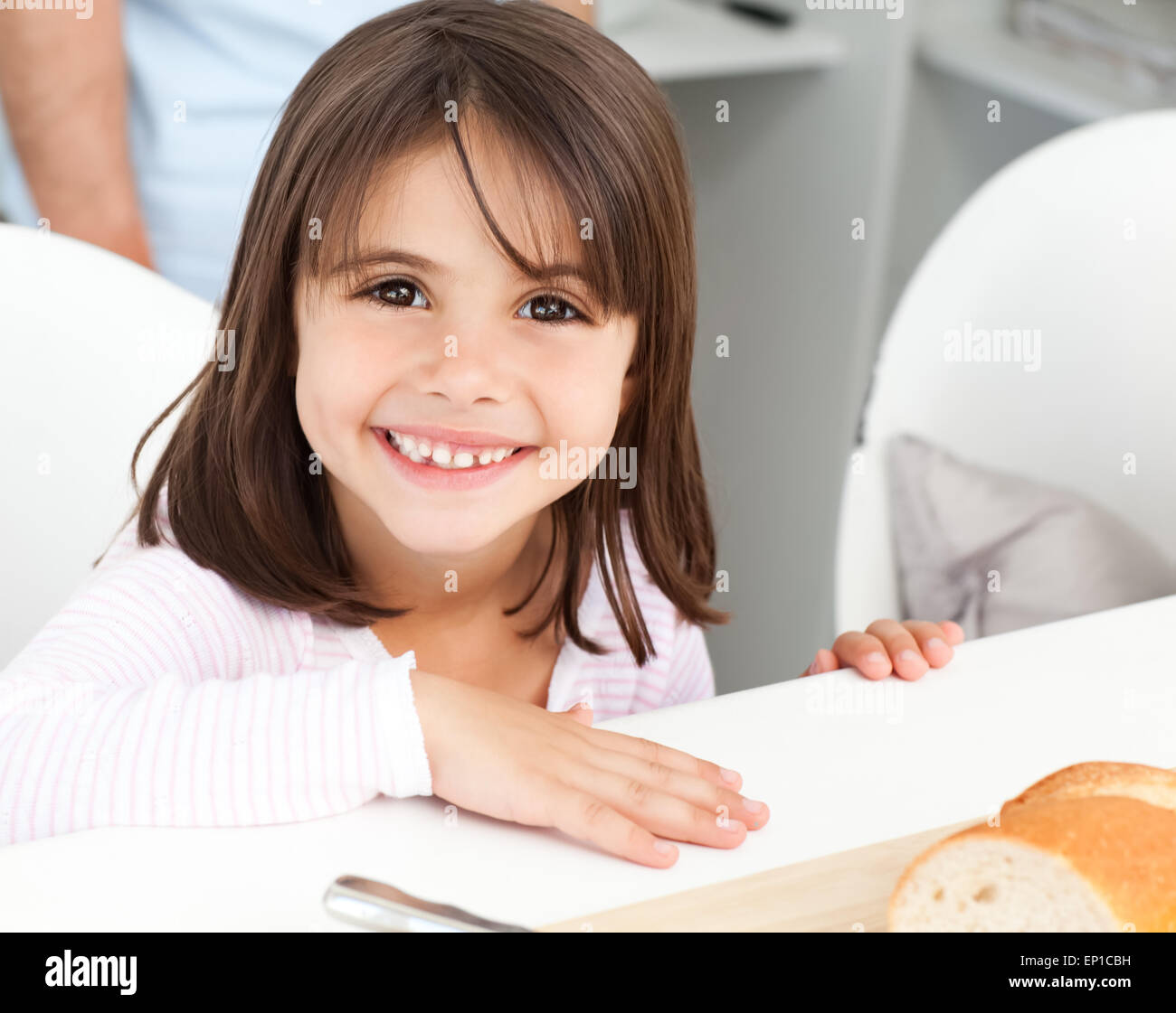 Cute little girl eating bread during breakfast Stock Photo - Alamy