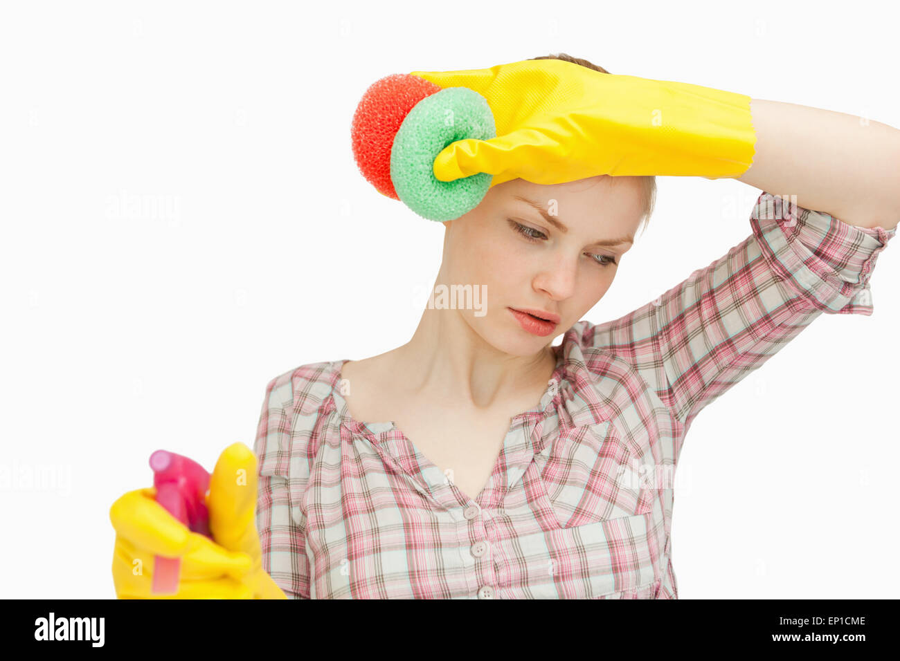 Young woman wiping her forehead while holding sponges Stock Photo - Alamy