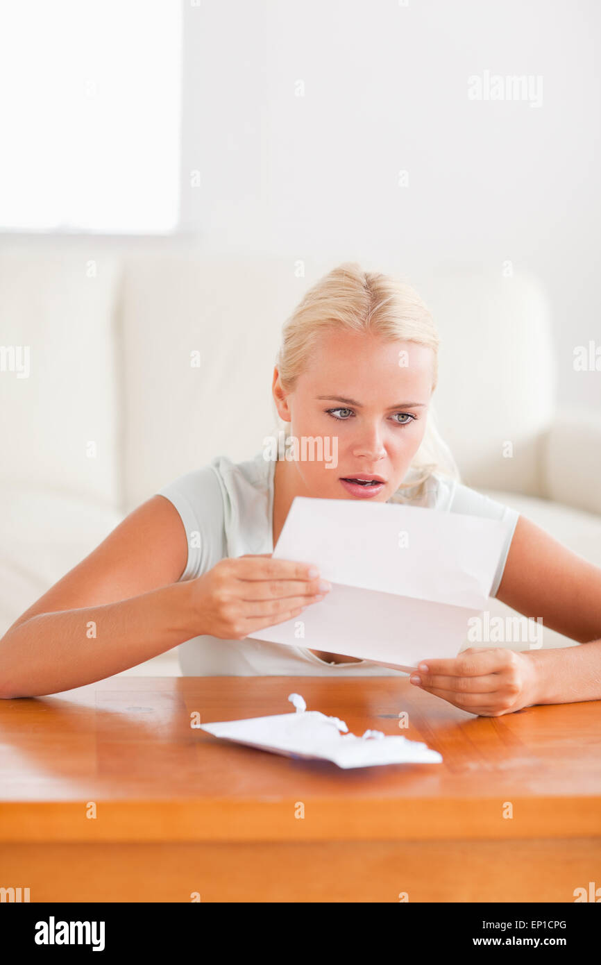 Woman looking at a letter in shock Stock Photo - Alamy