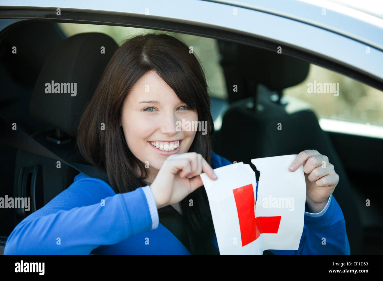 Jolly teen girl sitting in her car tearing a L-sign Stock Photo - Alamy