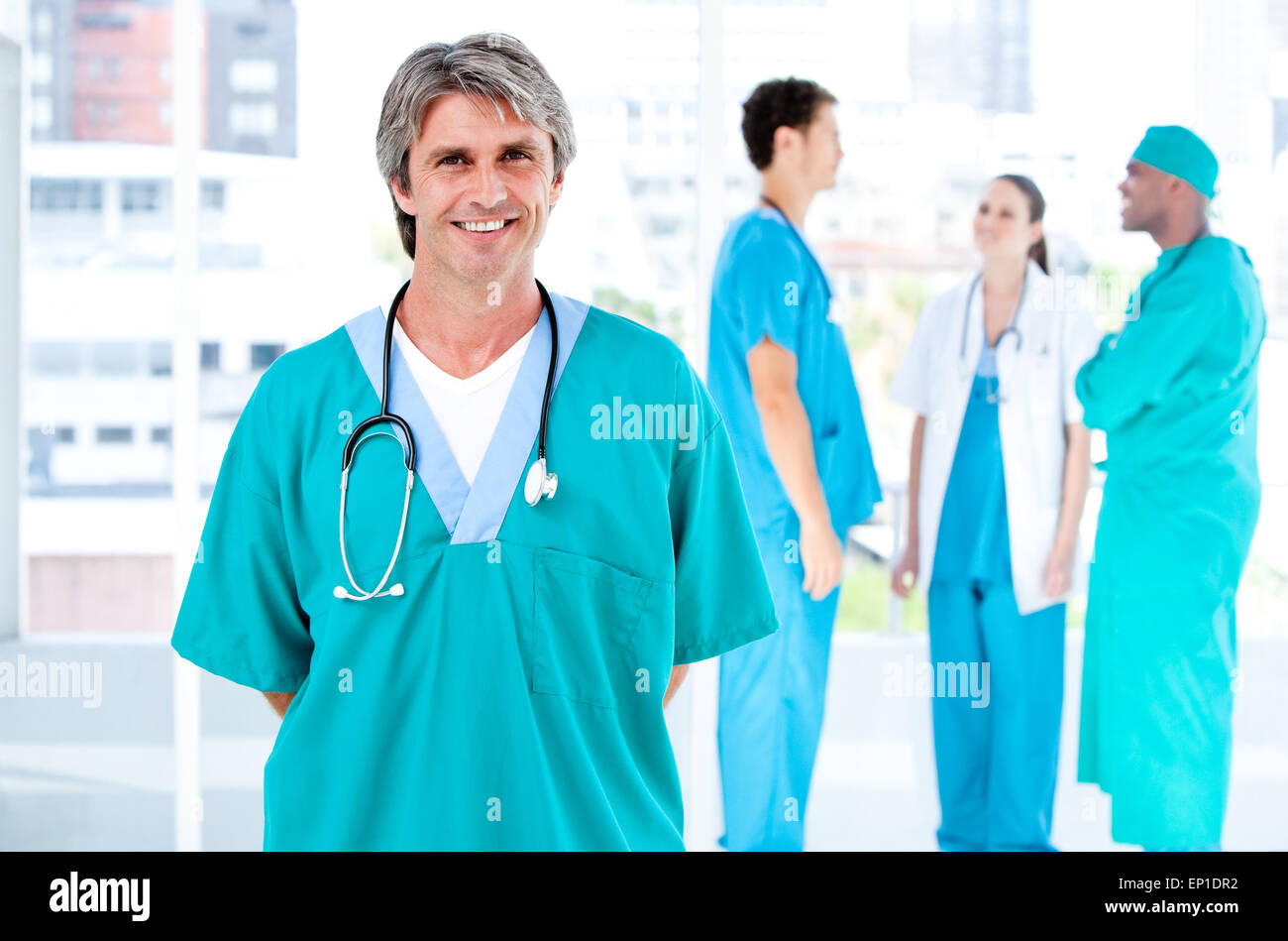 Joyful male doctor looking at the camera while his medical partners ...