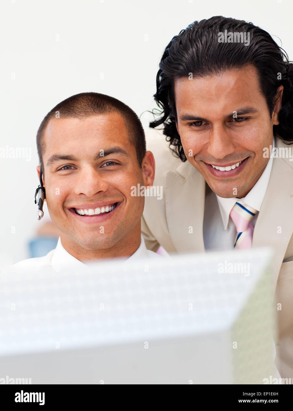 Smiling businessman helping his colleague at a computer Stock Photo - Alamy