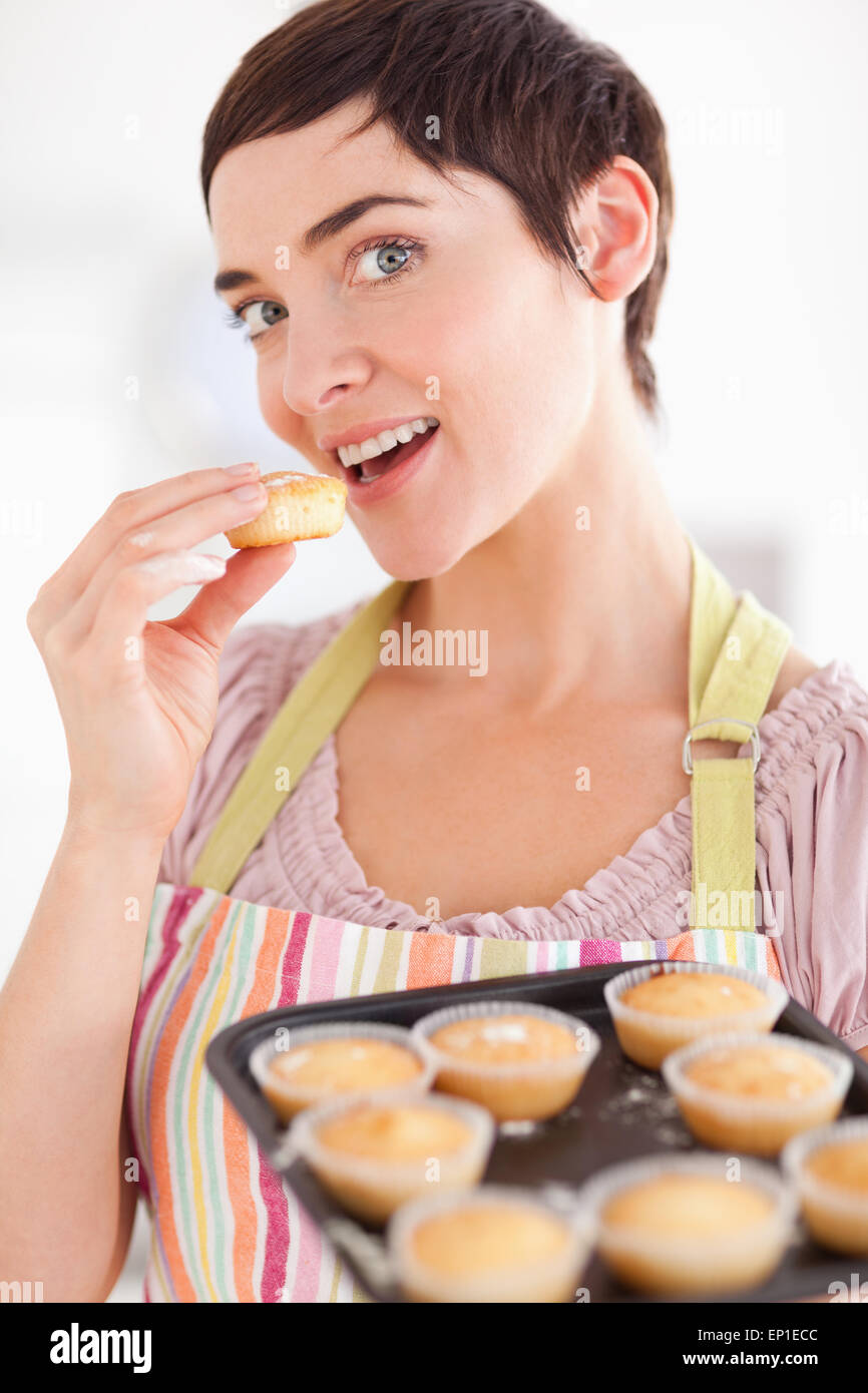 Charming brunette woman showing muffins while eating one Stock Photo ...