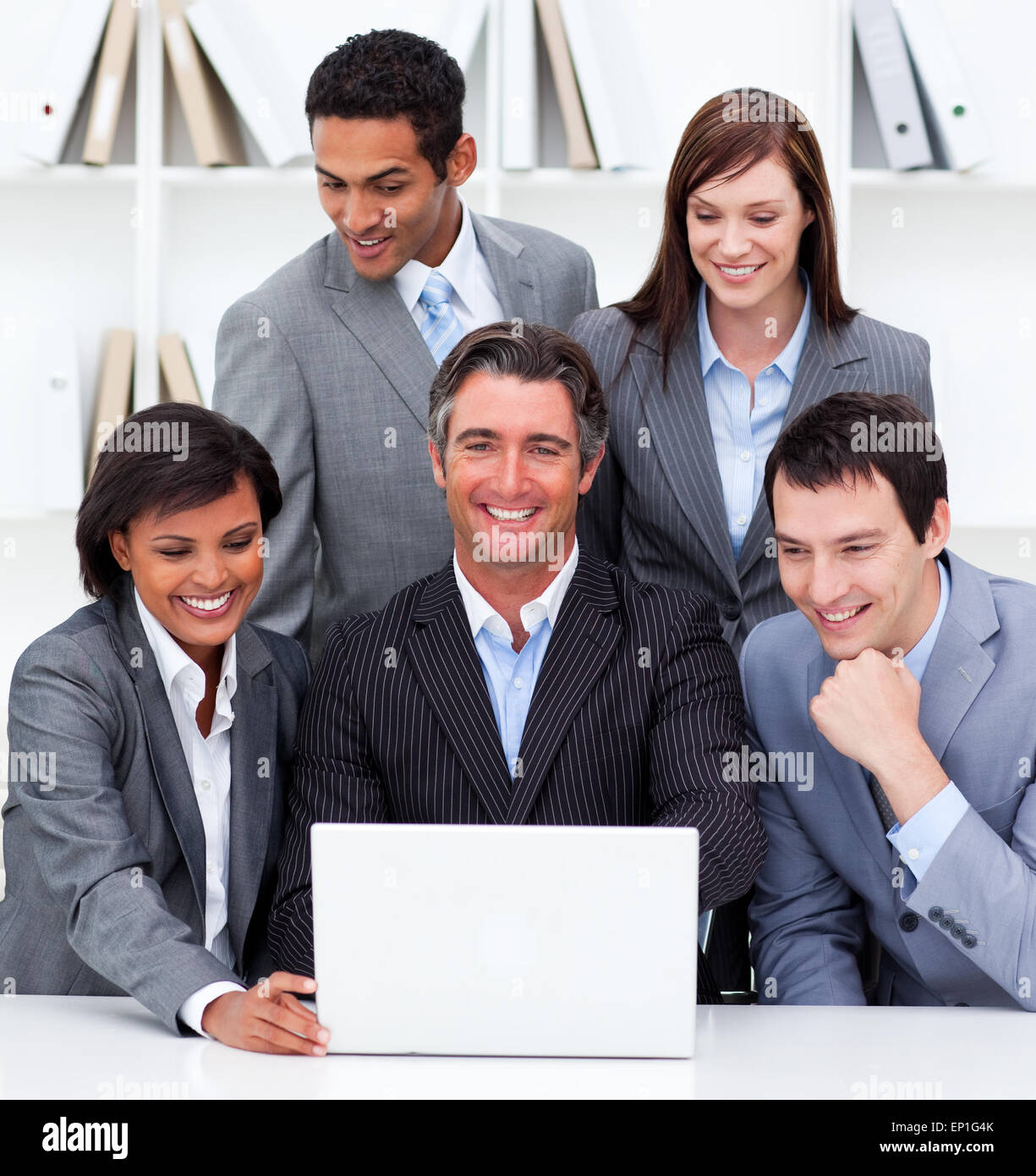 Cheerful business team looking at a laptop Stock Photo - Alamy