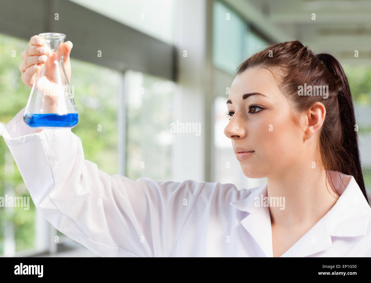 Cute science student looking at a blue liquid Stock Photo - Alamy