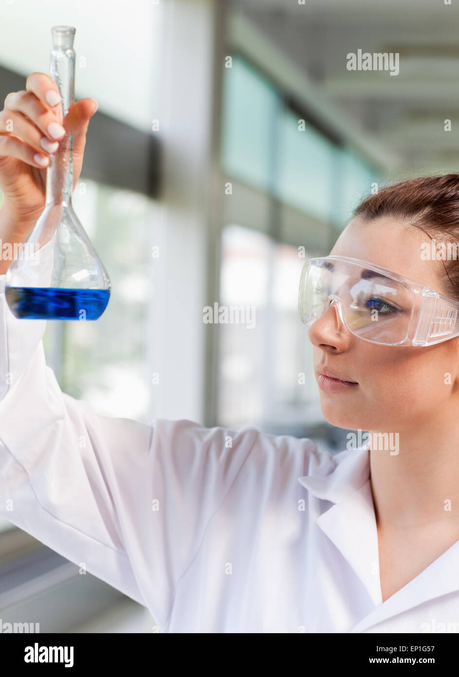 Portrait of a young science student looking at a blue liquid Stock ...