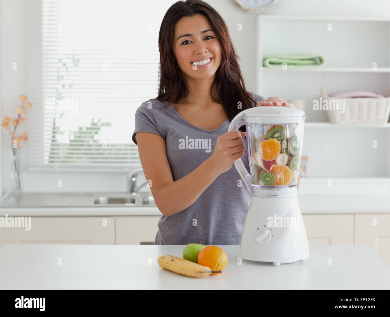 Attractive woman using a blender while standing Stock Photo - Alamy