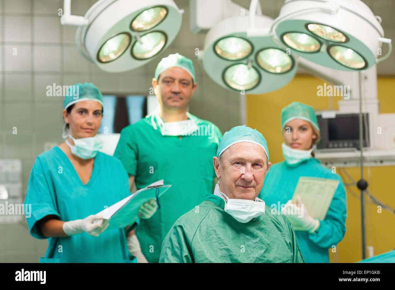 Smiling surgeon sitting with a team behind him Stock Photo - Alamy