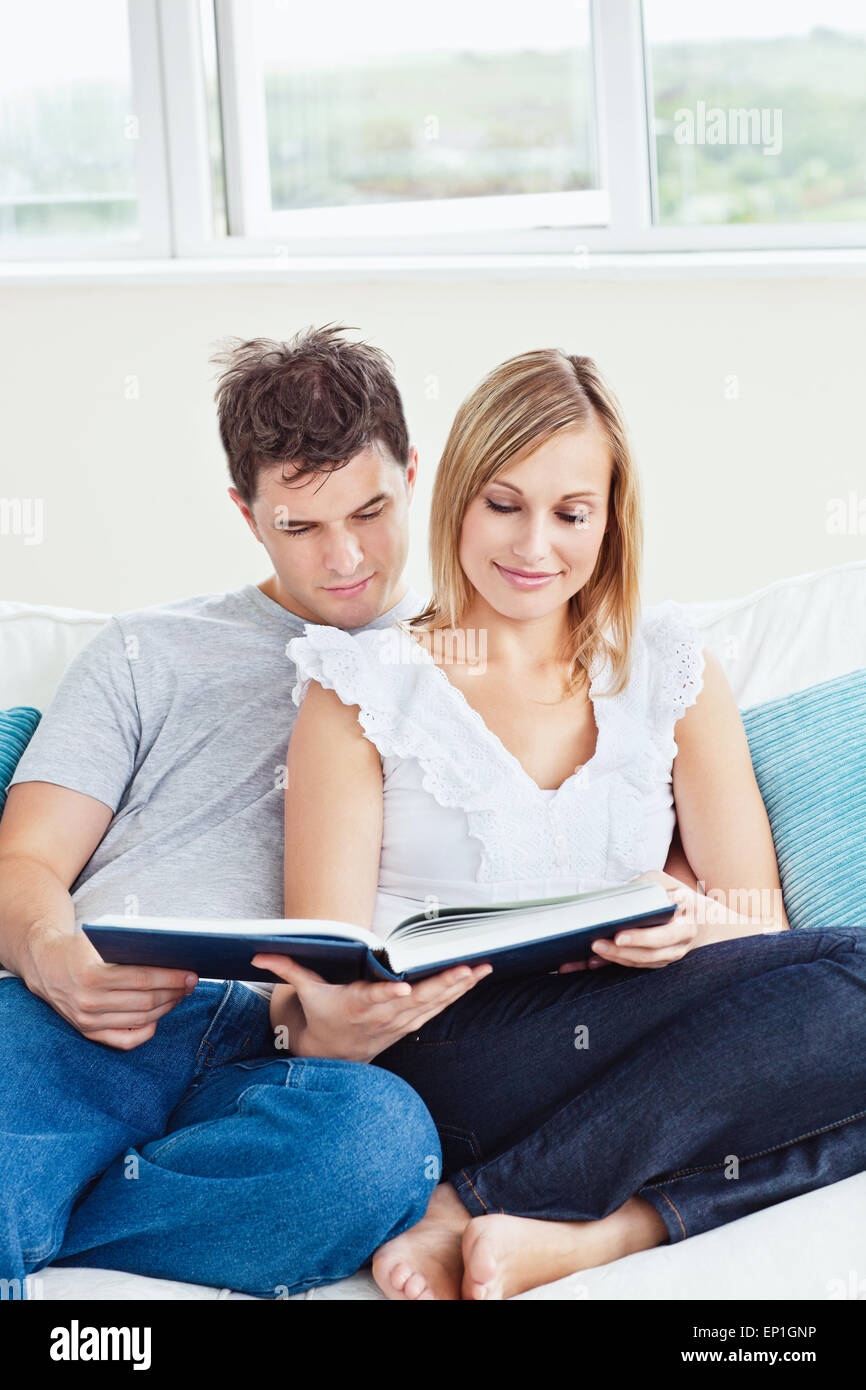 smart couple reading a book together sitting on the sofa Stock Photo ...