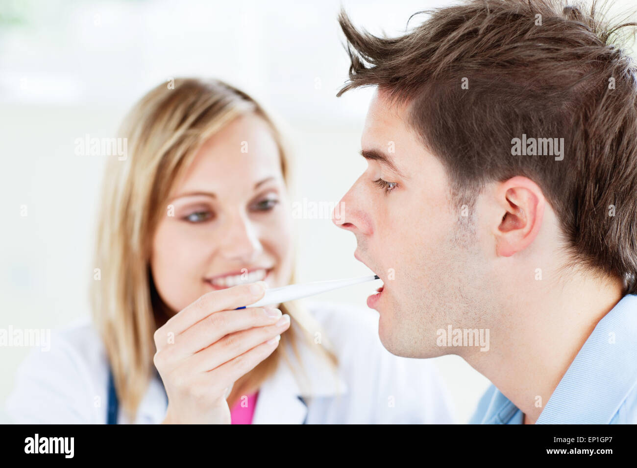 Woman doctor taking the temperature of her patient Stock Photo - Alamy