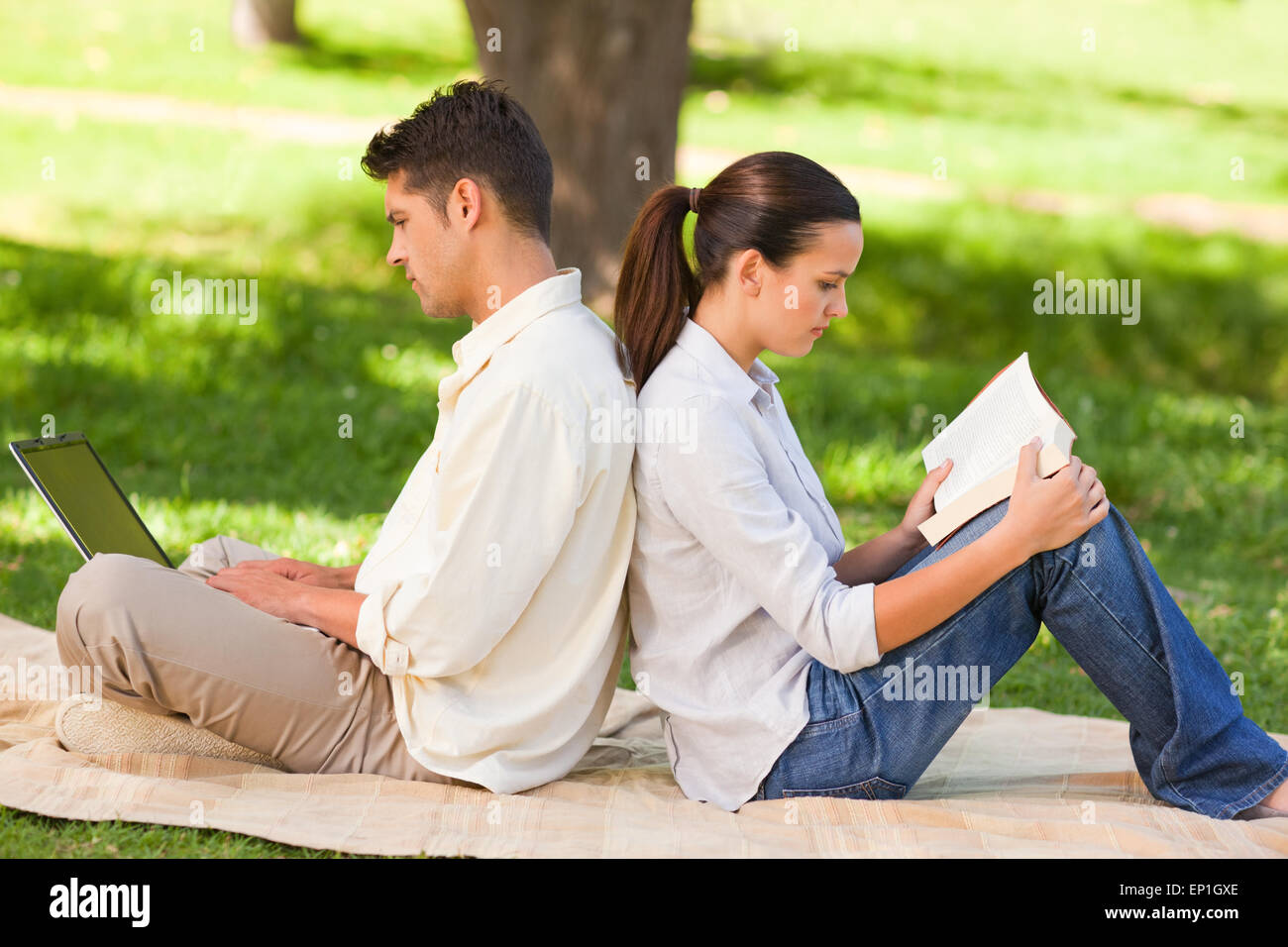 Man working on his laptop while his wife is reading Stock Photo - Alamy
