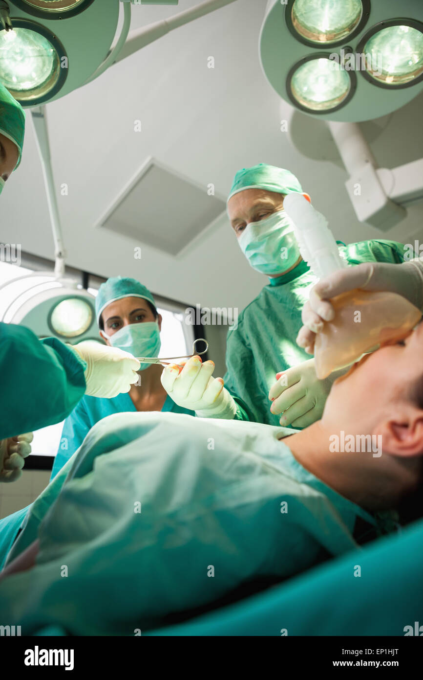 Oxygen mask placed in the face of a patient while a medical team is ...