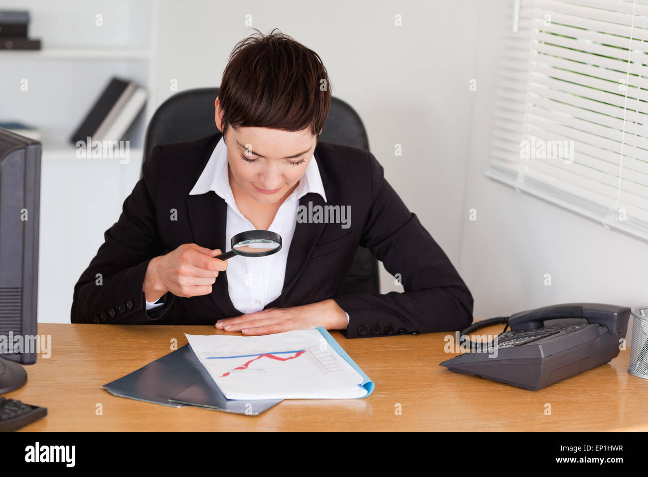 Woman looking at a chart with a magnifying glass Stock Photo - Alamy