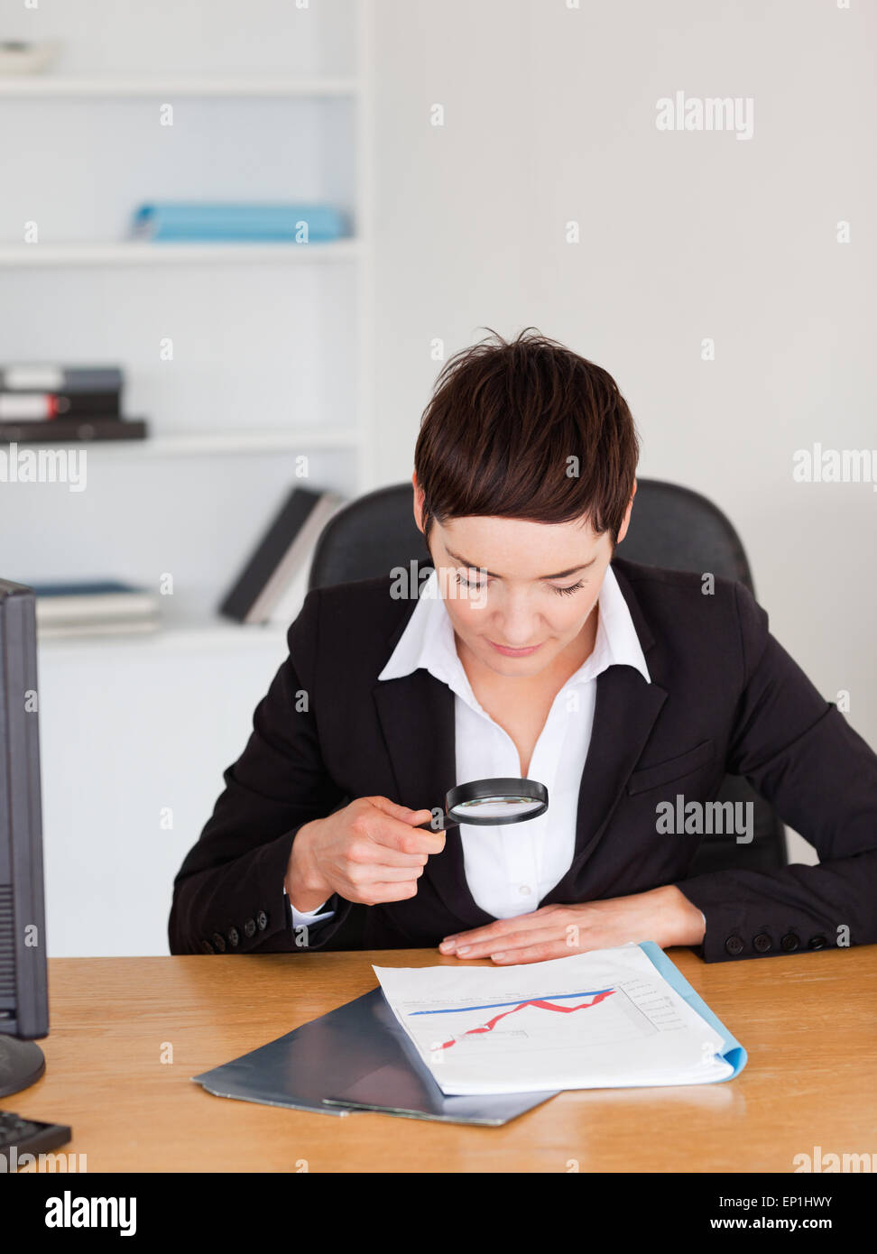 Portrait of a woman looking at a chart with a magnifying glass in her ...