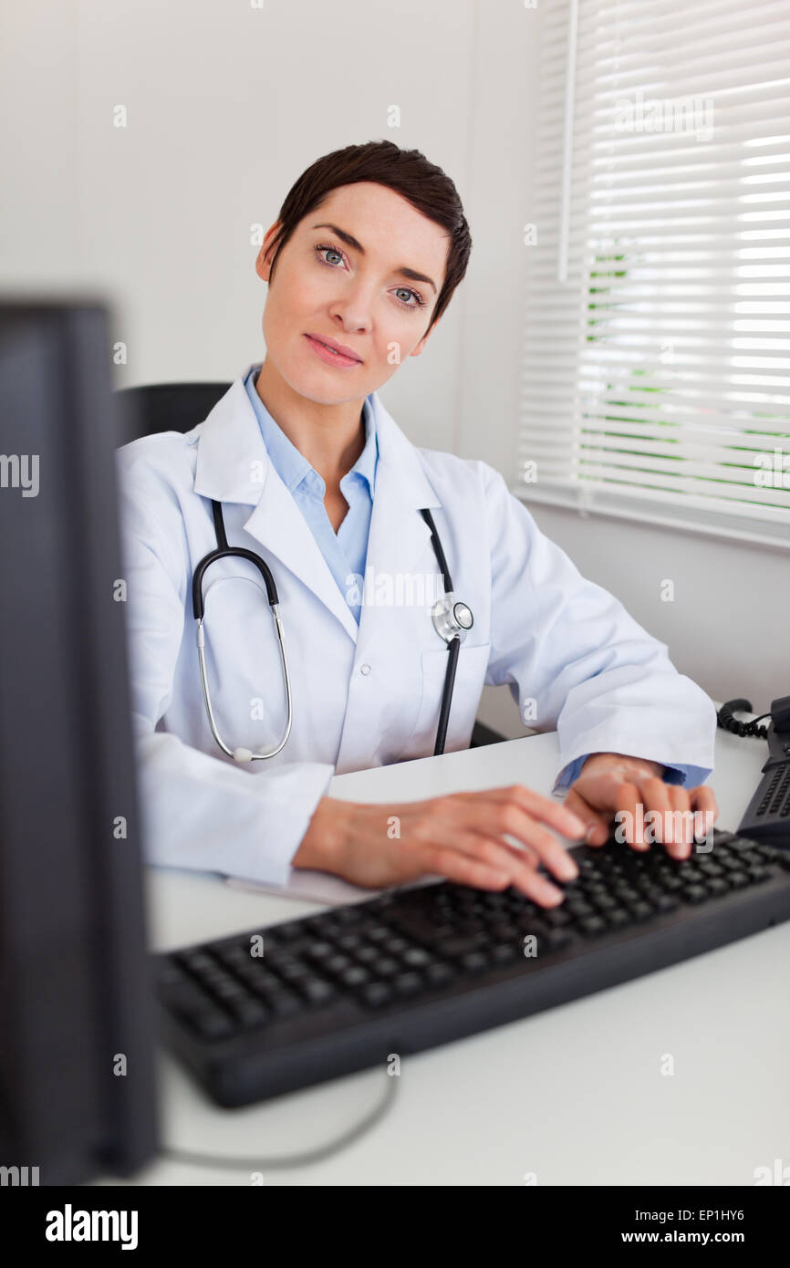 Portrait of a smiling female doctor typing with her computer Stock ...