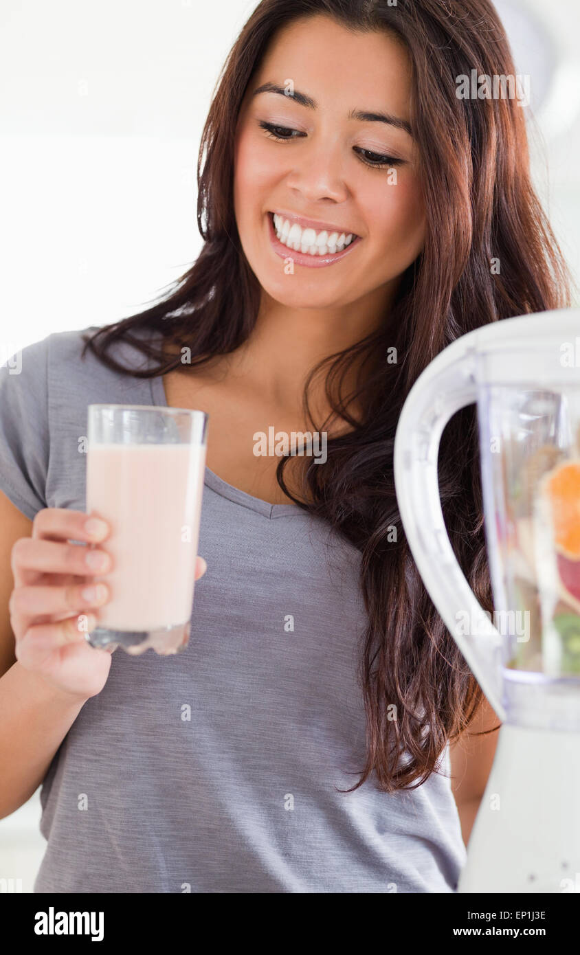 Pretty woman using a blender while holding a drink Stock Photo - Alamy