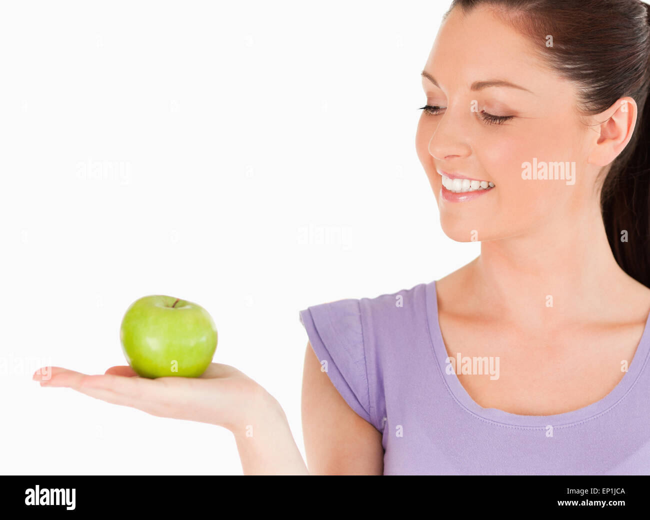 Charming woman holding an apple while standing Stock Photo - Alamy