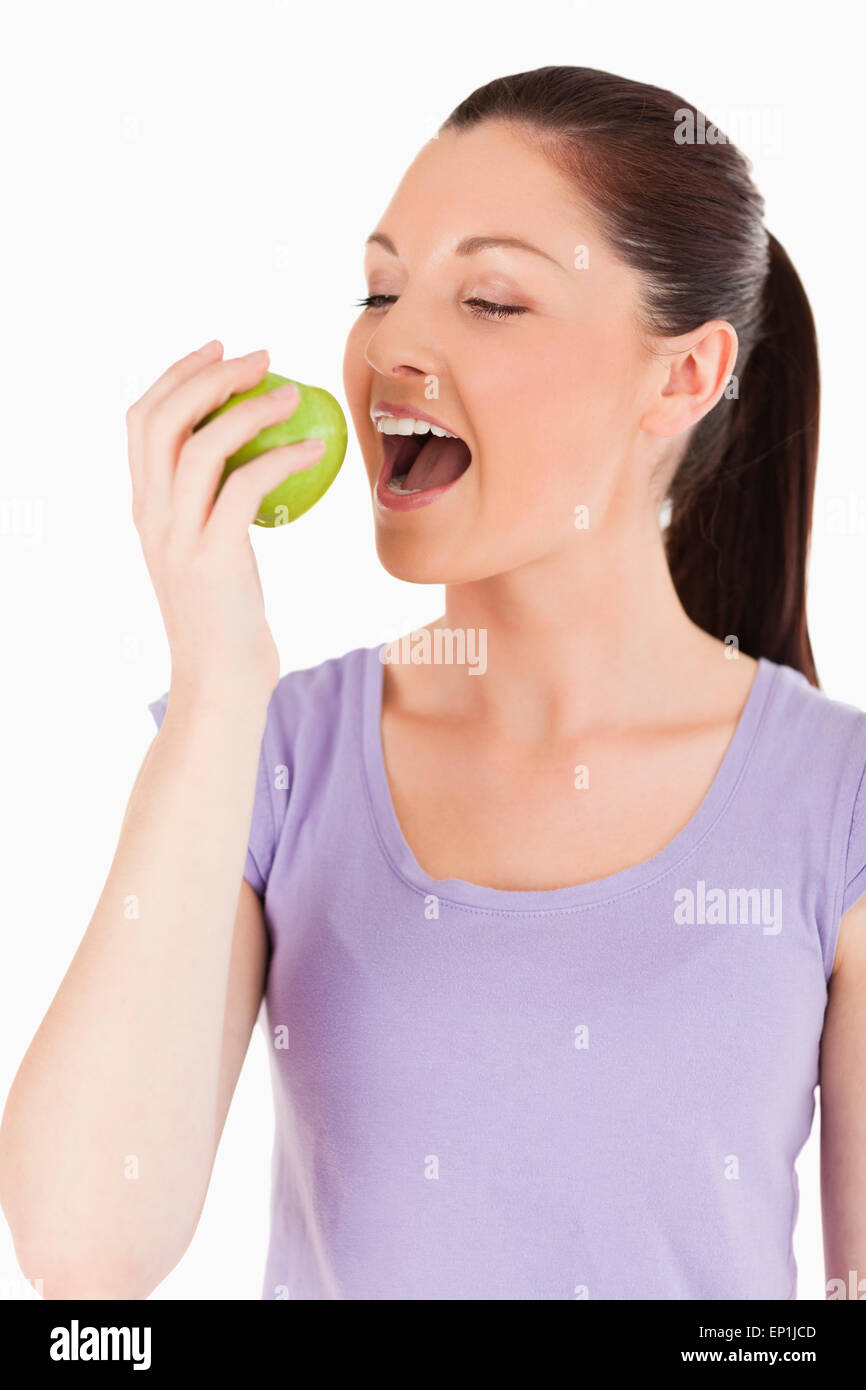 Beautiful woman eating an apple while standing Stock Photo - Alamy
