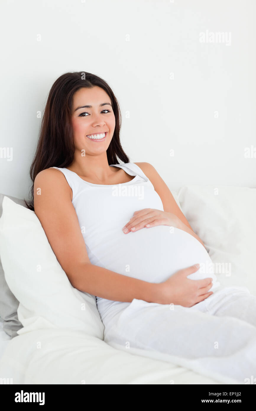Frontal View Of A Pretty Pregnant Woman Touching Her Belly While Lying