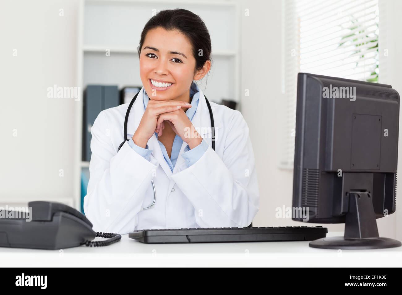Attractive woman doctor posing while sitting Stock Photo - Alamy