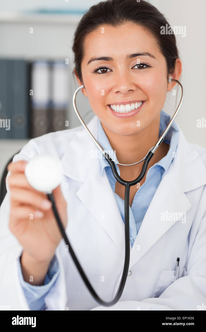 Good looking female doctor using a stethoscope while looking at the ...