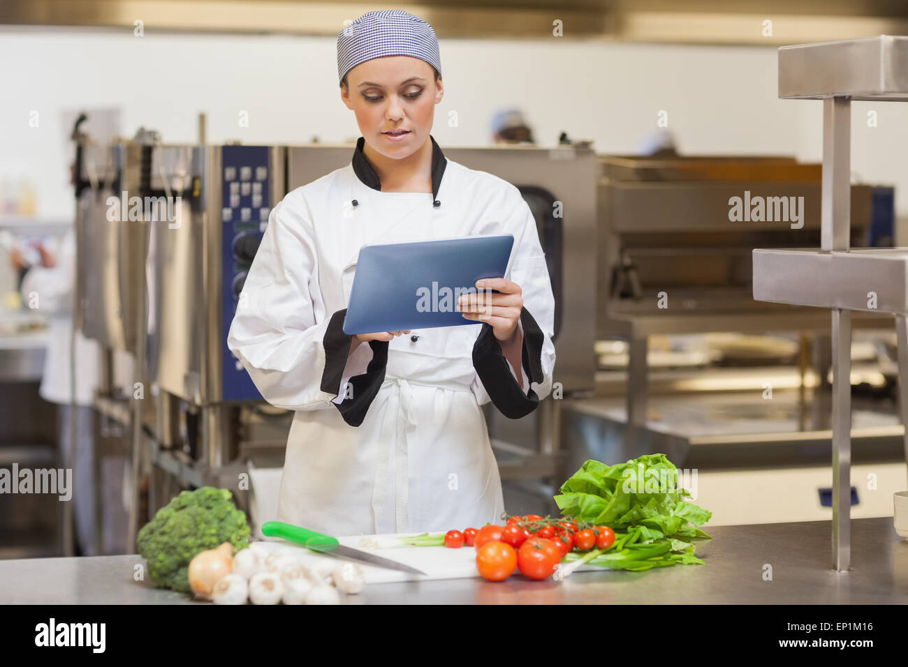 Serious chef using digital tablet beside the vegetables Stock Photo - Alamy