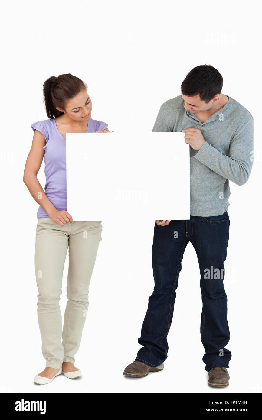 Young couple looking at sign they are holding Stock Photo - Alamy