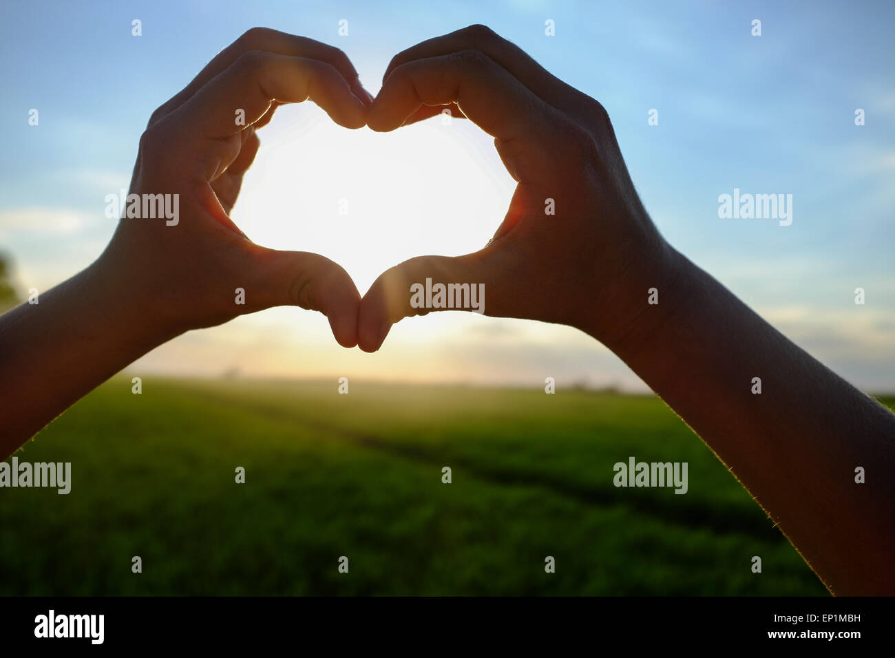Hands showing heart symbol, beautiful sunset landscape in the ... Hands showing heart symbol, beautiful sunset landscape in the ...
