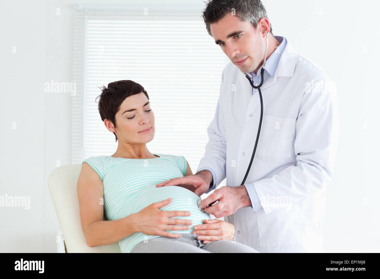 Male Doctor listening into the belly with a stethoscope Stock Photo - Alamy