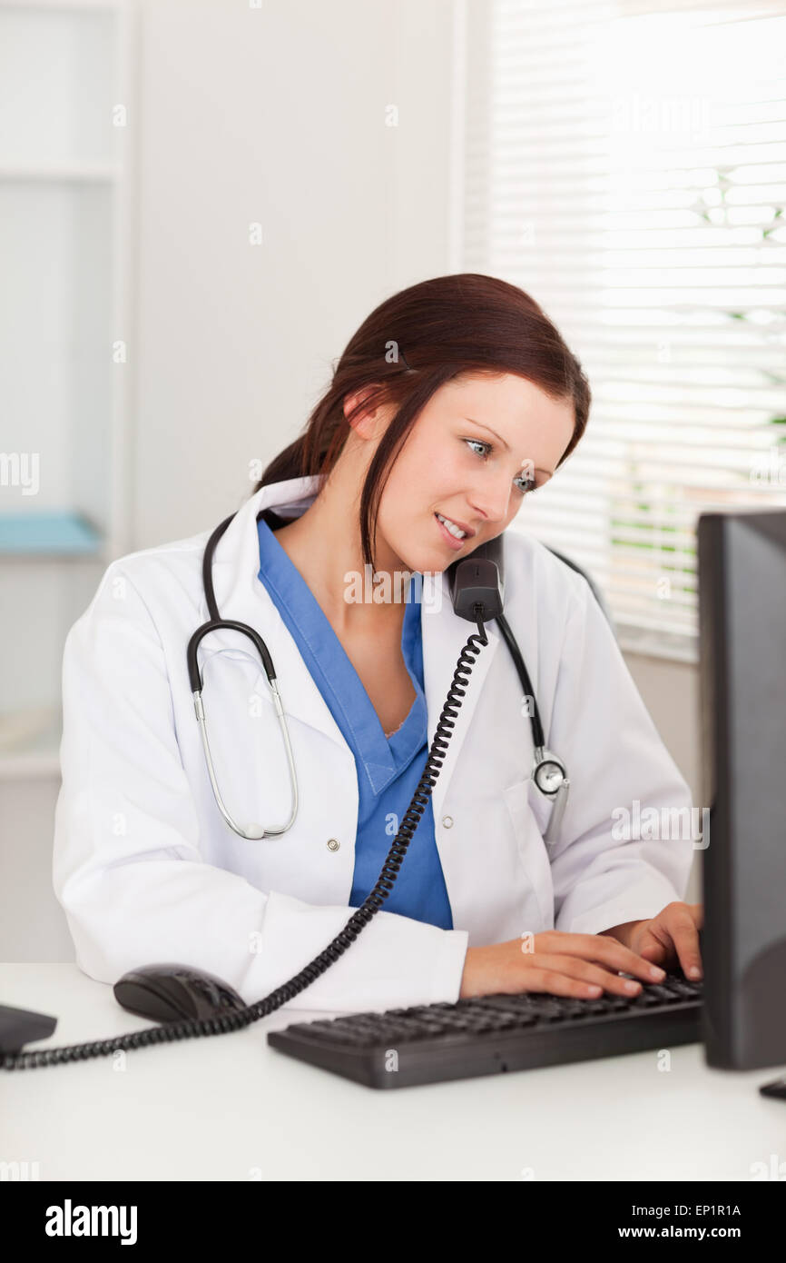Female doctor typing and telephoning Stock Photo - Alamy