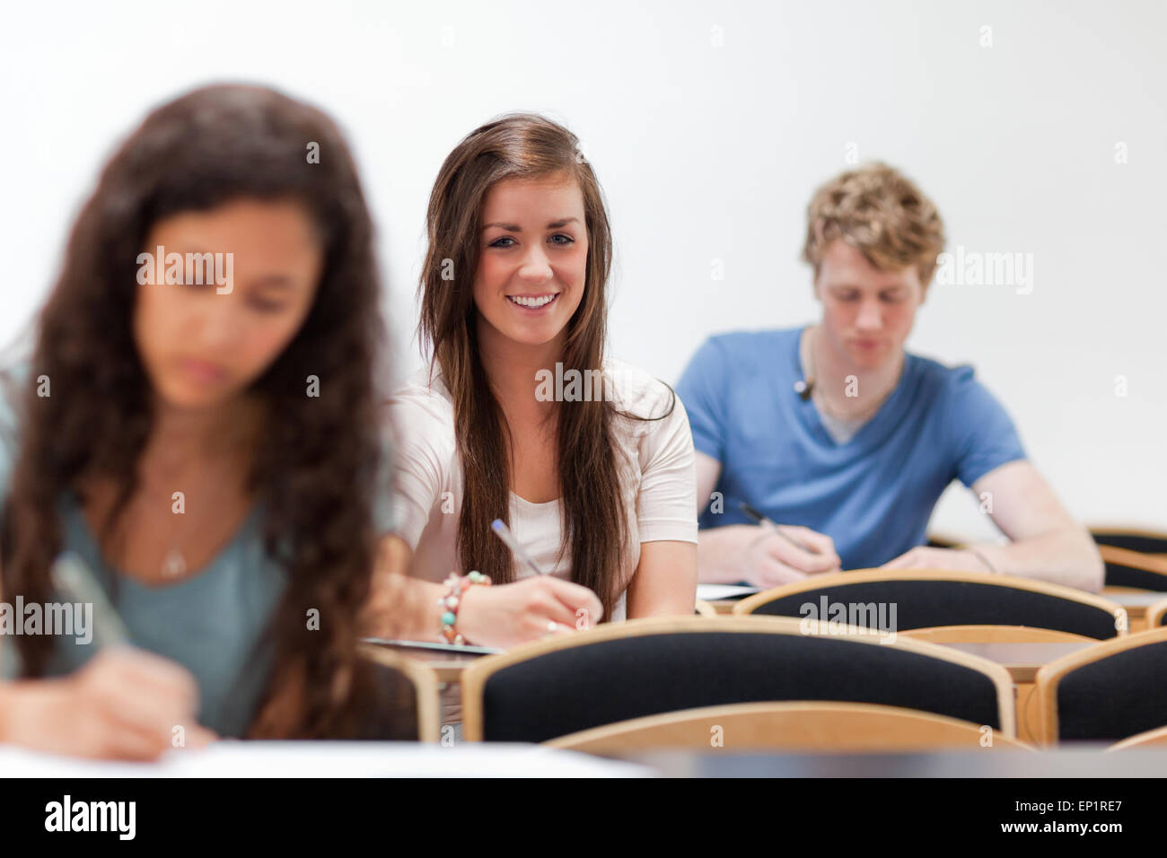 Smiling young students sitting on a chair Stock Photo - Alamy