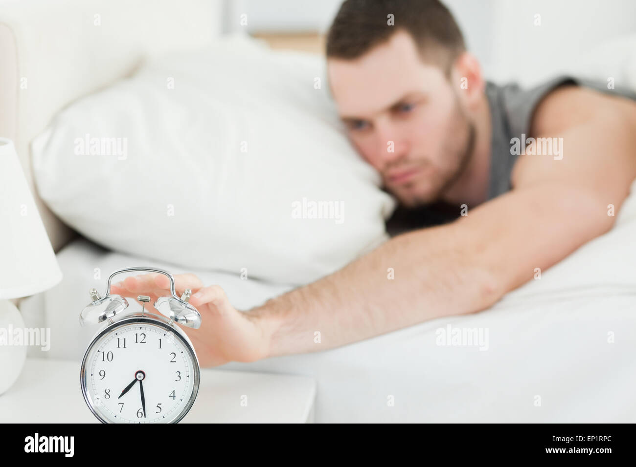 Tired man switching off his alarm clock Stock Photo - Alamy