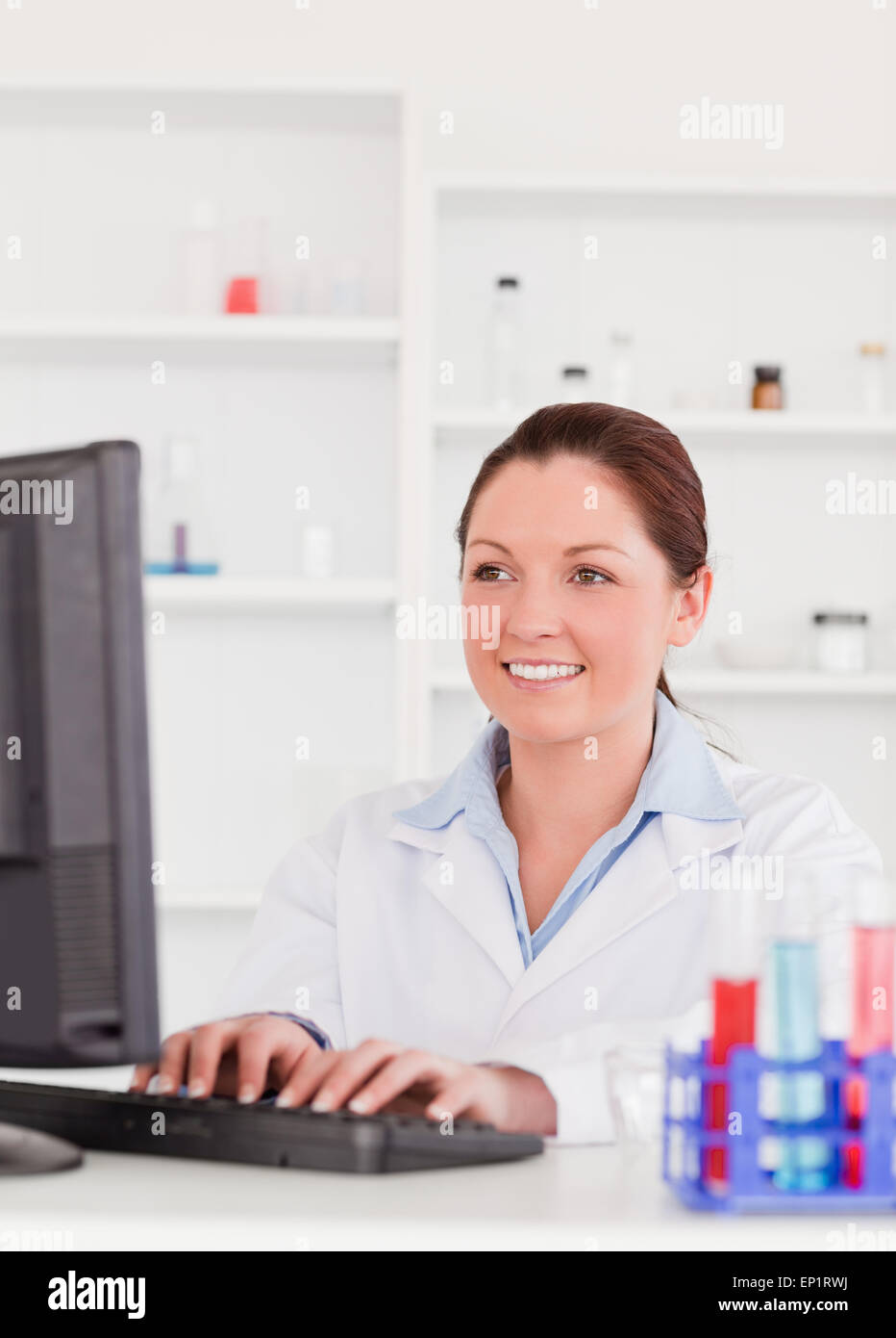 Smiling scientist typing a report with her computer Stock Photo - Alamy