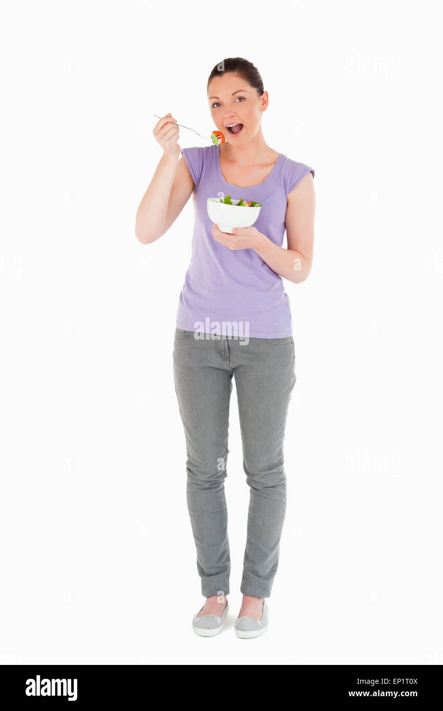 Gorgeous woman eating a bowl of salad while standing Stock Photo - Alamy