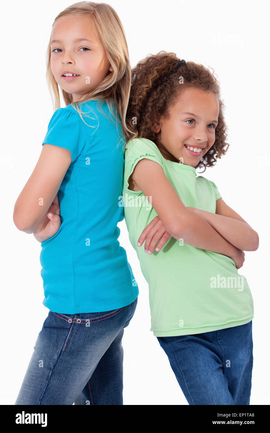 Portrait of smiling girls standing back to back Stock Photo - Alamy