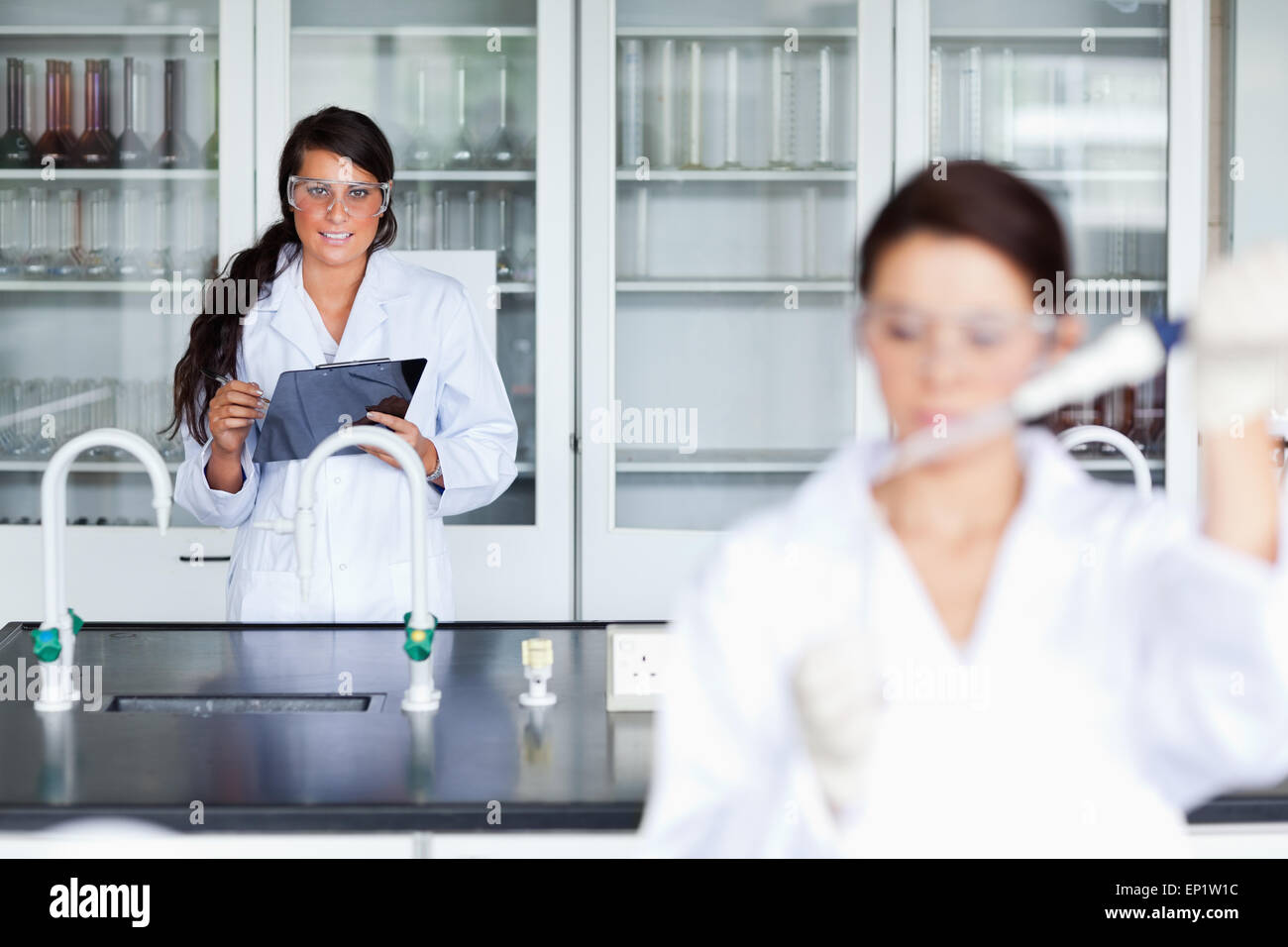 Female scientist writing on a clipboard Stock Photo - Alamy