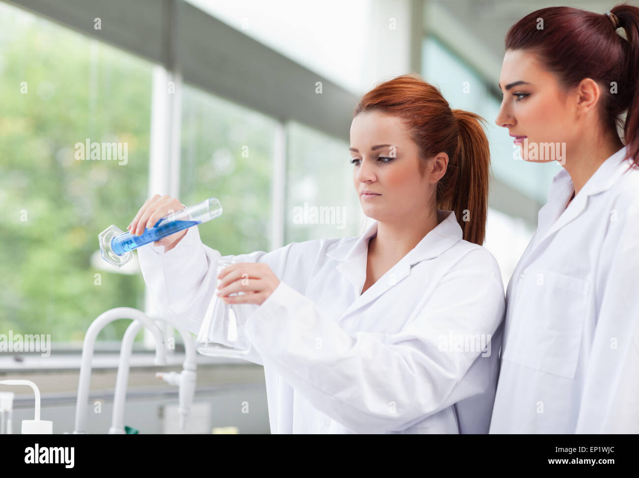 Science students pouring liquid in an Erlenmeyer flask Stock Photo - Alamy