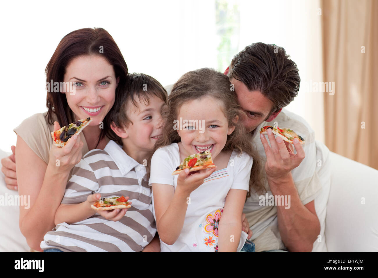 Smiling family eating pizza Stock Photo - Alamy