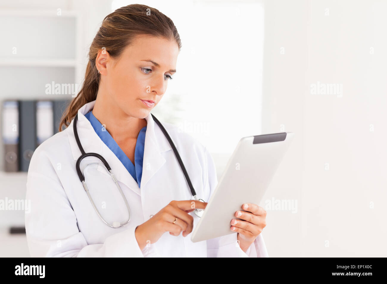 Charming doctor having a stethoscope around her neck looking at Stock ...