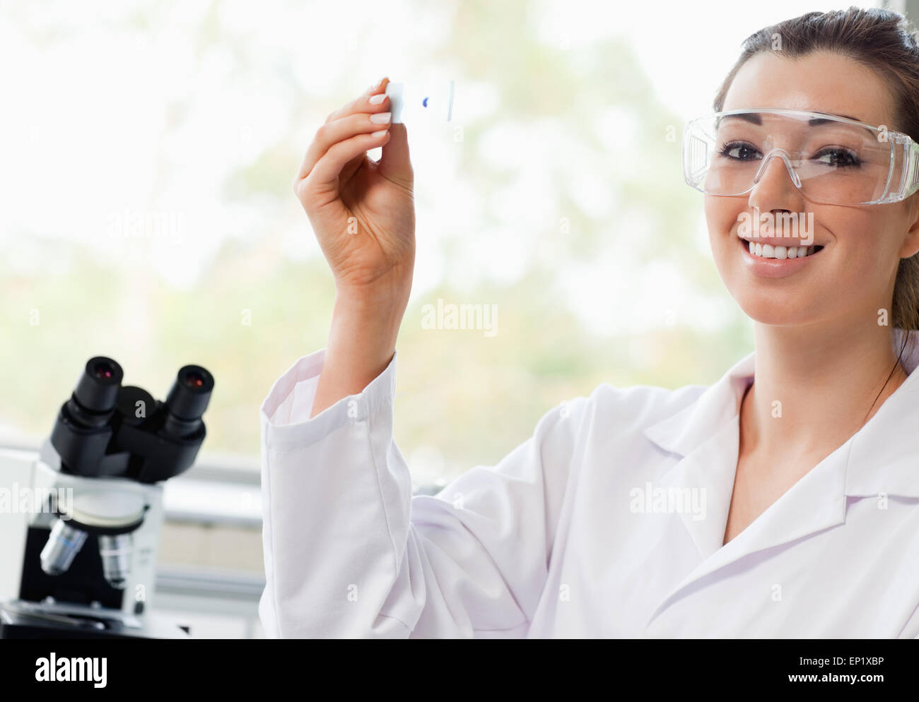 Smiling science student holding a microscope slide Stock Photo - Alamy