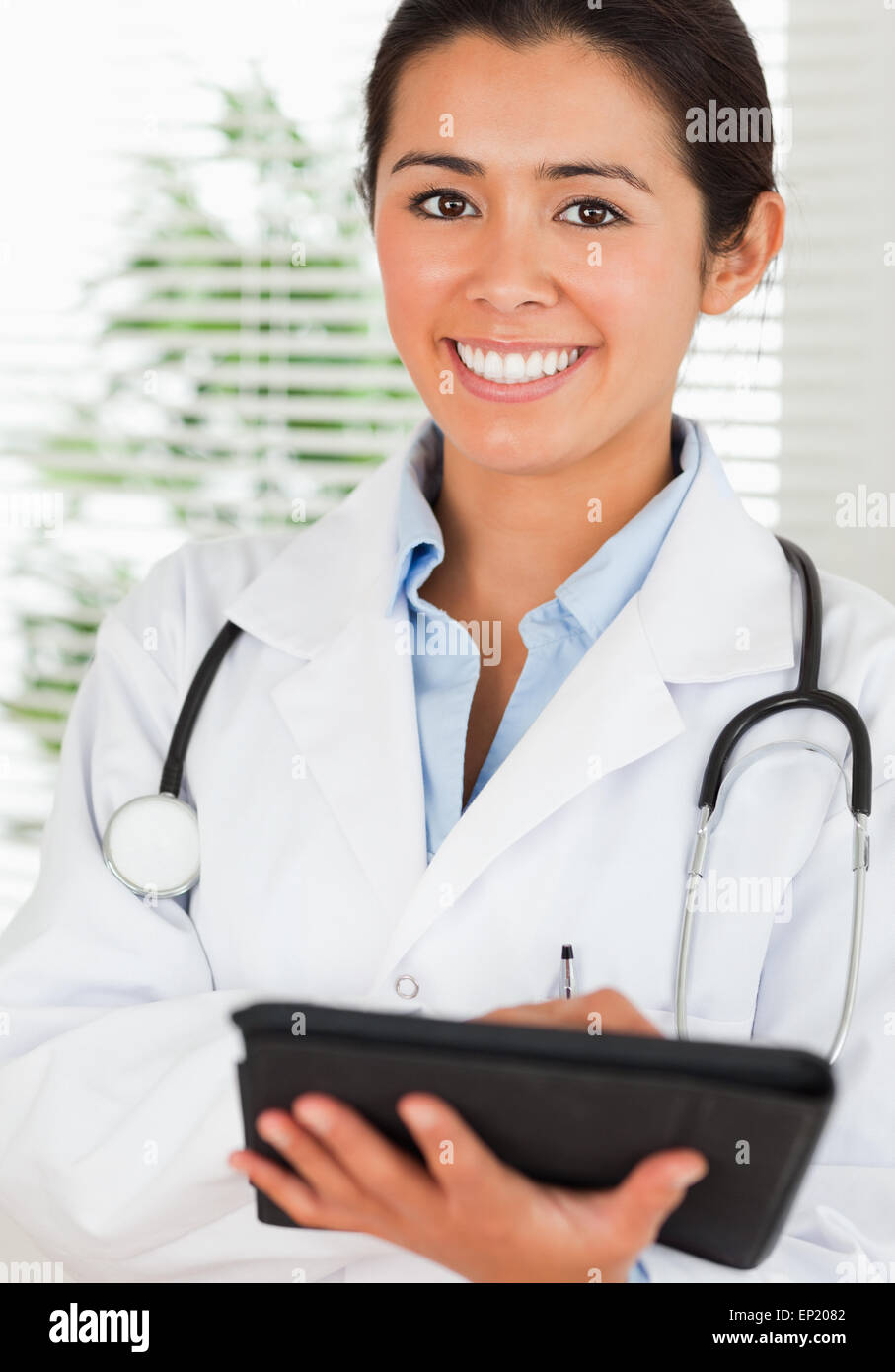 Good looking female doctor with a stethoscope writing on a notebook ...