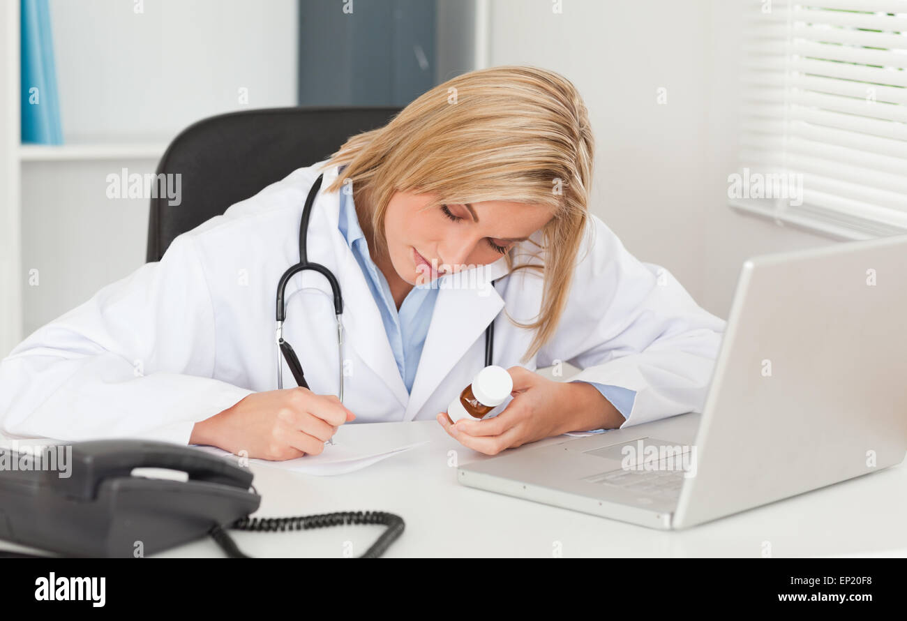 Doctor writing something down holding medicine Stock Photo - Alamy