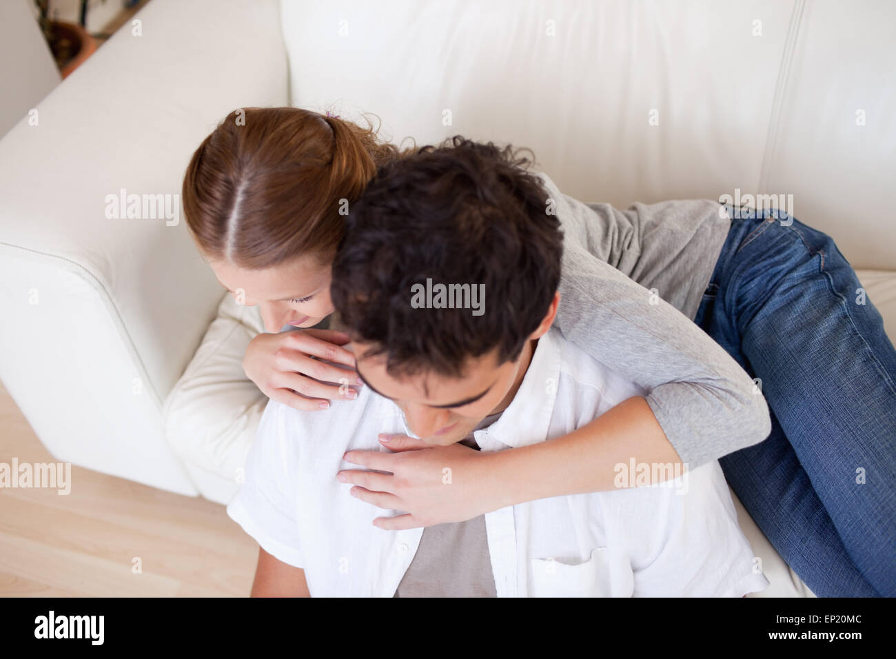 Woman hugging her boyfriend on the sofa Stock Photo - Alamy
