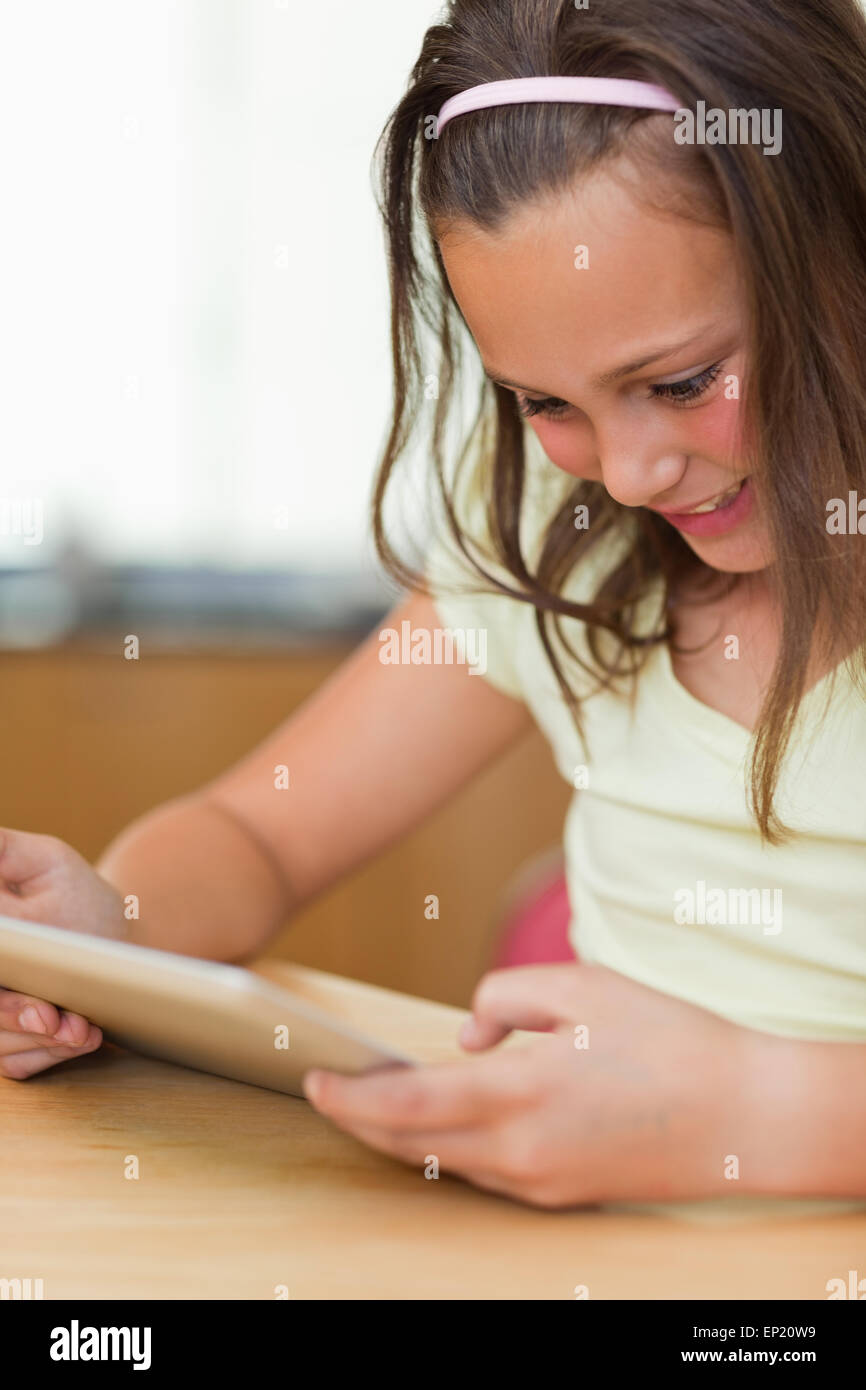 Girl sitting at kitchen table while looking at tablet Stock Photo - Alamy