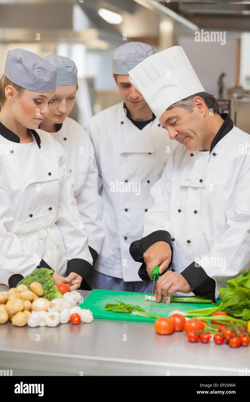 Chef teaching cutting vegetables to three trainees Stock Photo - Alamy