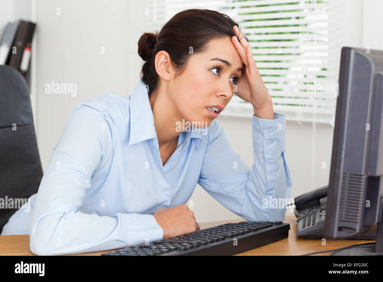 Beautiful upset woman looking at a computer screen while sitting Stock ...