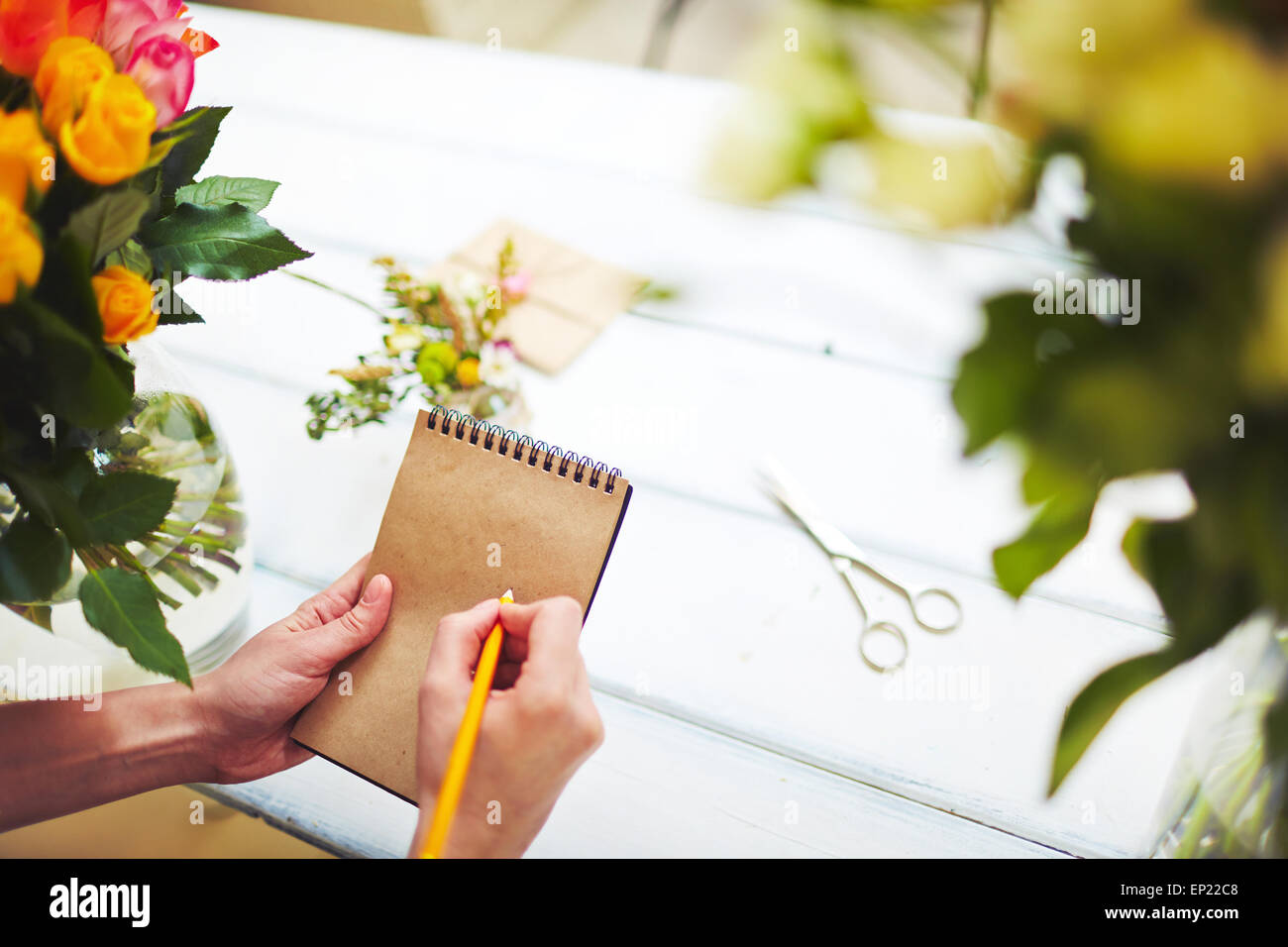 Florist with pencil making notes in notepad over workplace Stock Photo ...